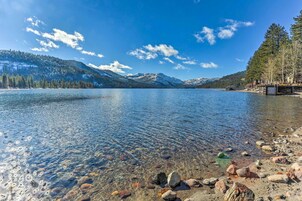 Um lago límpido com rochas visíveis e um cais que se estende sobre a água.