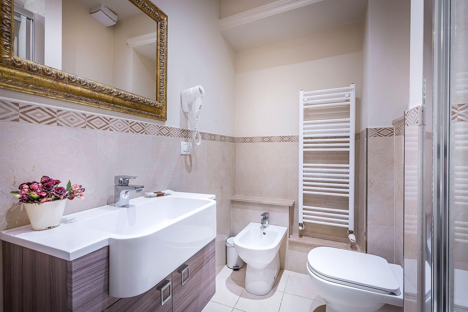 Uma casa de banho moderna com uma grande lavatório branco, um bidé, uma sanita e área de chuveiro.