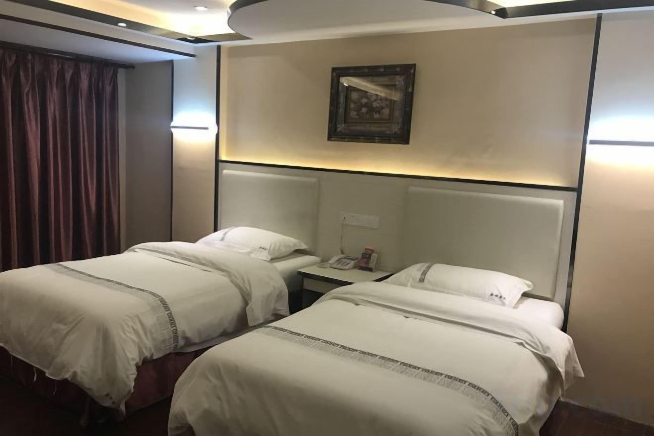 Quarto de hotel com duas camas, uma mesa de cabeceira, uma luminária e um quadro na parede.