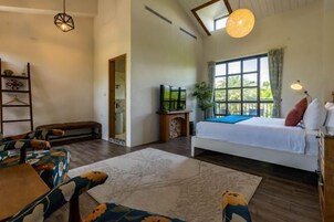 Quarto com cama, escrivaninha, cadeira, luminária pendente e janela.