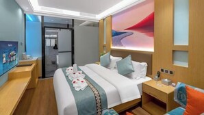 Quarto de hotel moderno com uma cama grande, uma escrivaninha e uma televisão.