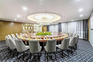 Sala de conferência com mesa redonda, cadeiras e lustre.