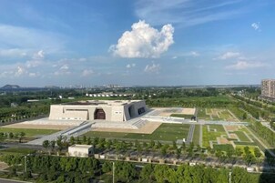 Um edifício amplo com um pátio central, rodeado por vegetação e um céu claro.