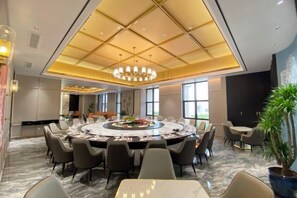 Sala de conferências com mesa redonda, cadeiras e lustre.