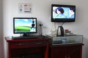 Um quarto com uma escrivaninha, monitor de computador, televisão e um aquário.