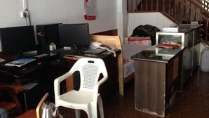 Quarto com escrivaninha, dois monitores, uma cadeira, uma cama e uma escada.
