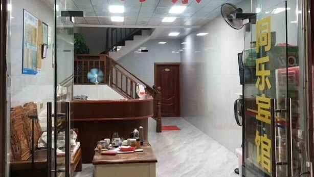 Um saguão de hotel com escadaria, balcão de recepção e parede de vidro com sinalização.
