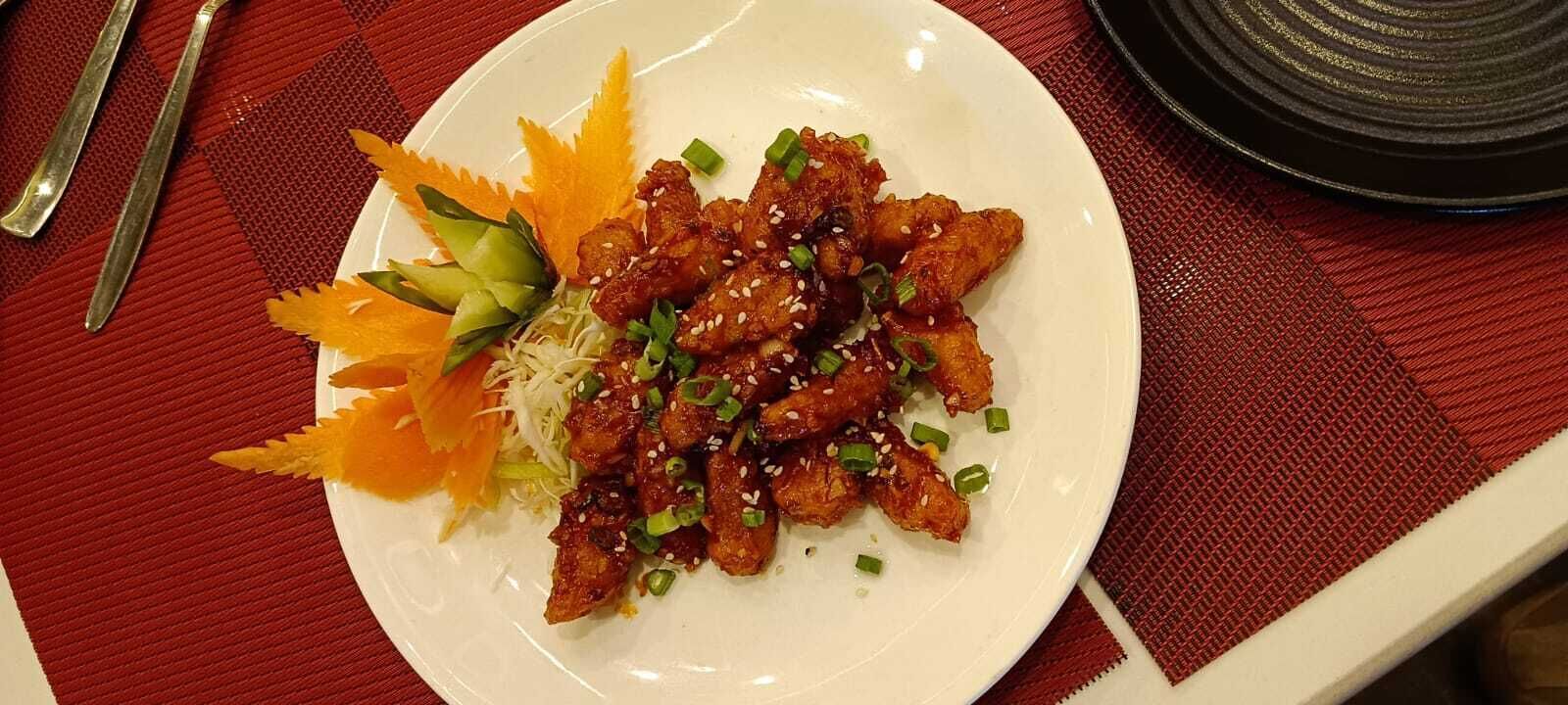Prato de comida com sementes de gergelim e cebolinha, acompanhado por um jogo americano vermelho.