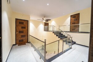 Um interior moderno com escada em guarda-corpo de vidro, porta de madeira e ventilador de teto.