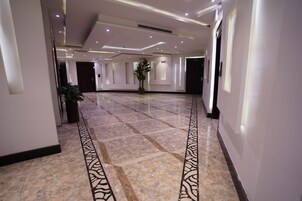 Um corredor amplo e bem iluminado, com piso de mármore polido e luminárias modernas.