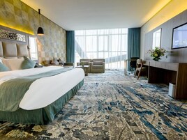 Quarto de hotel com uma cama grande, uma mesa, uma cadeira e uma televisão.