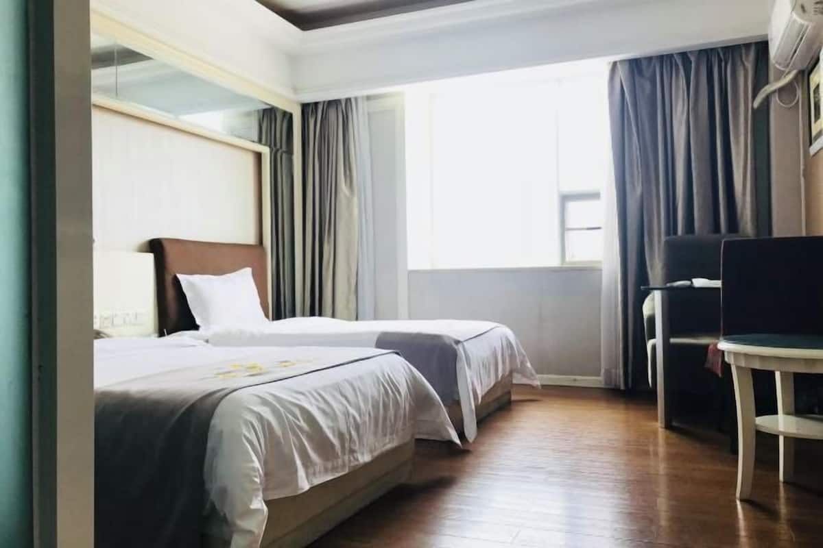 Quarto de hotel com duas camas, uma mesa e uma cadeira.