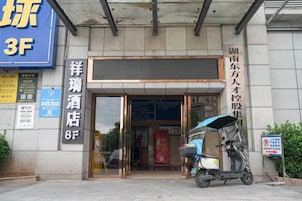 Entrada de um edifício com placa de hotel à esquerda e placa de empresa à direita.
