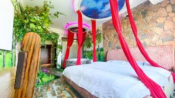 Quarto com cama, dossel vermelho, parede de pedra e vegetação.