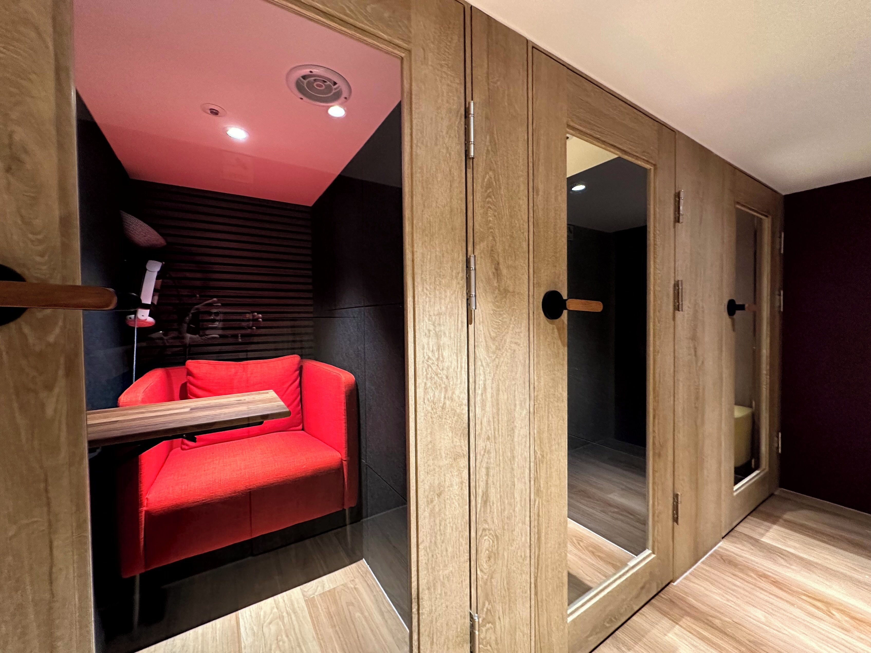 Um quarto com um sofá vermelho, um guarda-roupa de madeira e uma porta de closet com espelho.