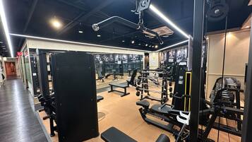 Uma academia com diversos equipamentos de exercícios, incluindo aparelhos de musculação e bancos.