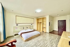 Quarto de hotel com cama, escrivaninha, armário e porta.