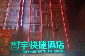 Fachada de um hotel com letreiros iluminados e número de contato.