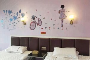 Quarto de hotel com cama, duas mesas de cabeceira e parede decorada com arte que inclui flores, uma bicicleta e uma menina.