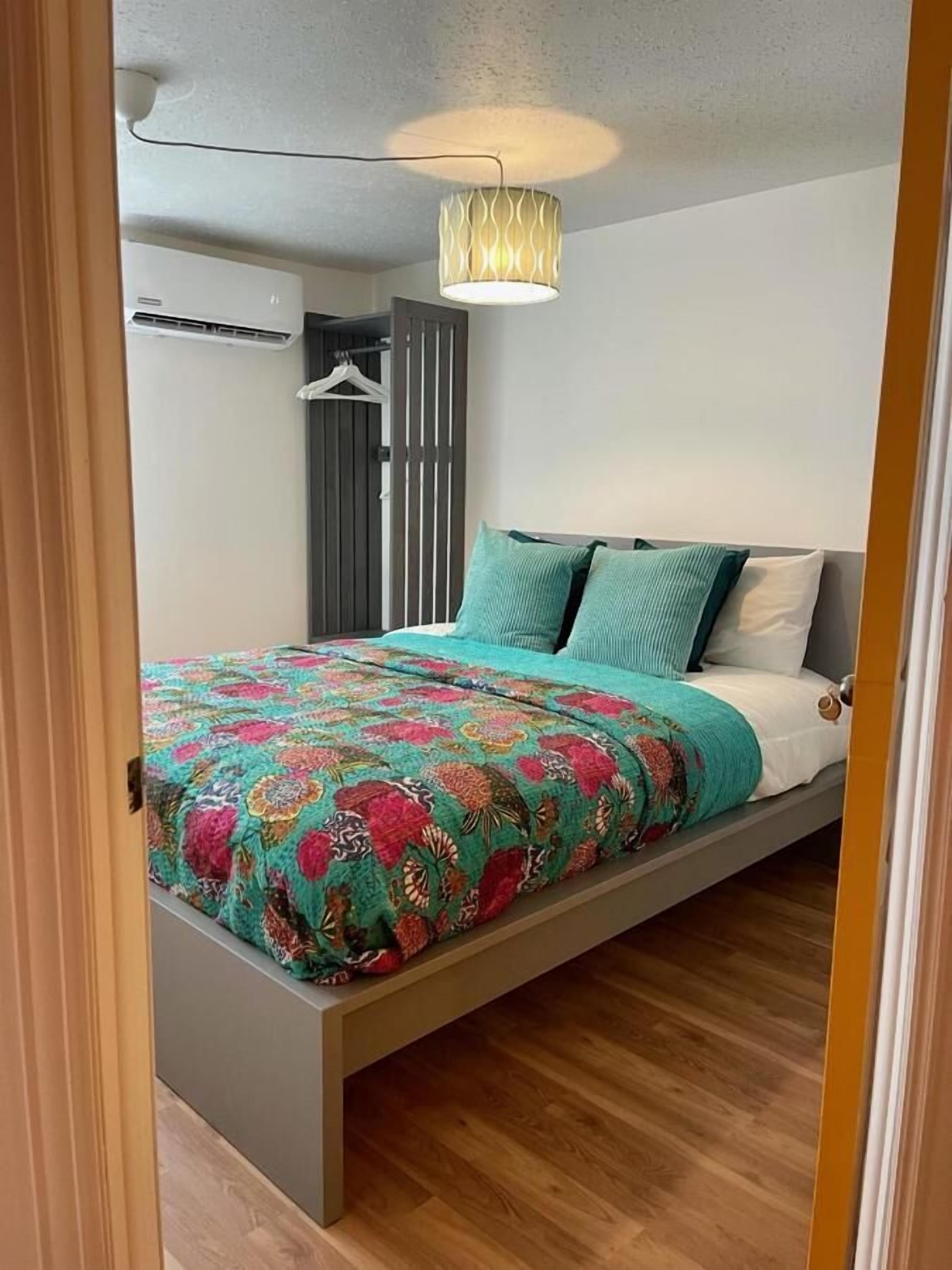Quarto com cama, luminária pendente e guarda-roupa.