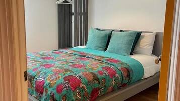 Quarto com cama, luminária pendente e guarda-roupa.