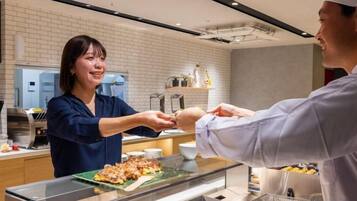 Uma pessoa entrega um alimento a outra em uma cozinha moderna.