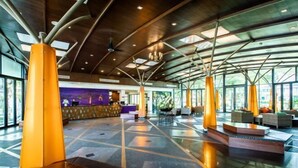 Um hall amplo com design moderno, com área de recepção, sofás e grandes janelas que permitem a entrada de luz natural.