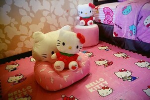 Quarto decorado com tema de Hello Kitty, com bichos de pelúcia e colcha com estampa da Hello Kitty.