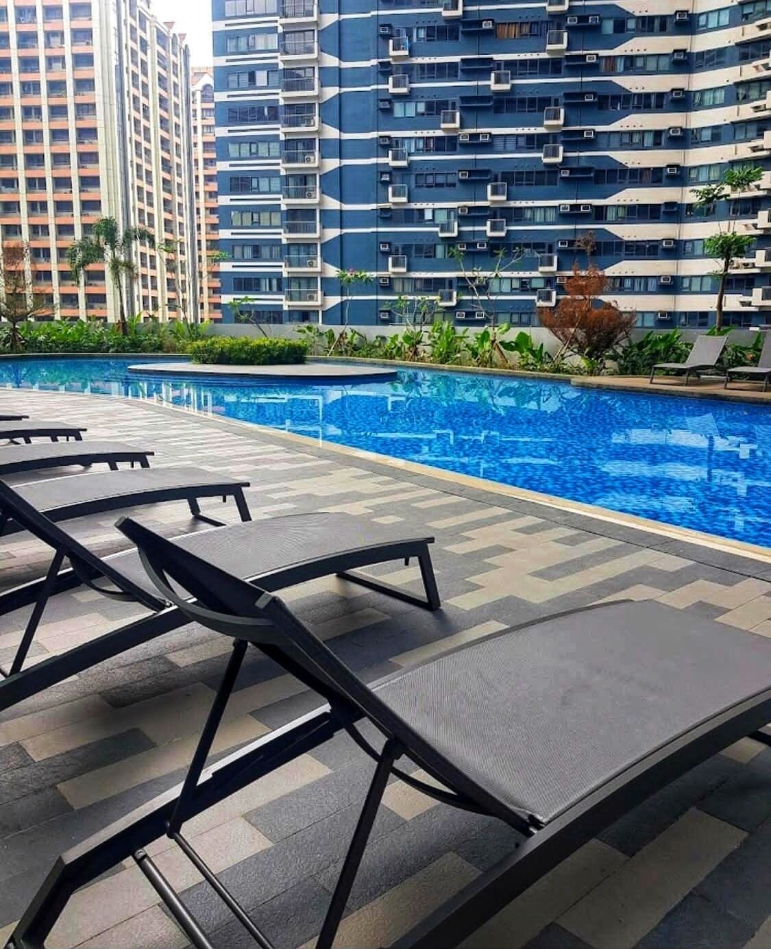 Piscina com espreguiçadeiras e vista para edifícios altos.