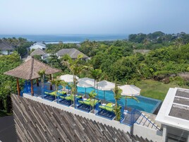 Um resort com área de piscina, espreguiçadeiras e vista para o oceano.