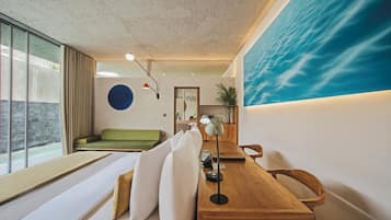 Um interior moderno com mesa de jantar de madeira, sofá verde e uma grande janela com vista para a água.