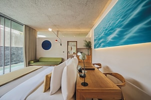 Um interior moderno com mesa de jantar de madeira, sofá verde e uma grande janela com vista para a água.