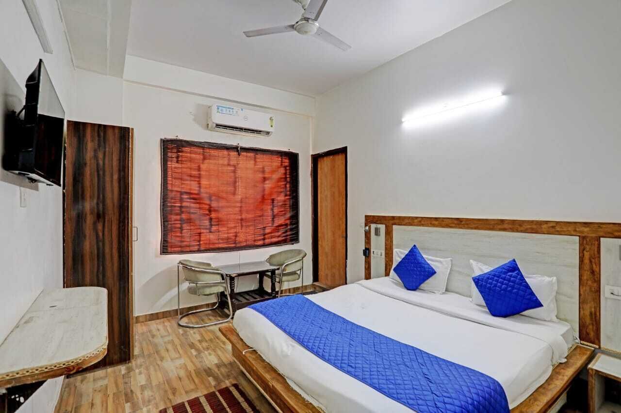Quarto de hotel com cama, escrivaninha, cadeira, televisão e ar condicionado.