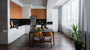 Uma cozinha moderna com armários de madeira, bancada preta e um espaço de refeições com mesa e cadeiras.