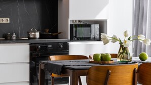 Uma cozinha moderna com uma bancada de mármore preto, armários de madeira e uma área de jantar com mesa posta para dois.