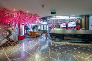 Um hall com balcão de recepção, área de estar e planta decorativa.