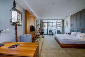 Quarto de hotel com cama, escrivaninha, cadeira, televisão e vista para a cidade.