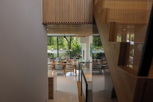 Interior moderno com área de jantar, janelas amplas e escada.