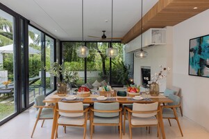 Área de jantar moderna com uma mesa grande, cadeiras e vista para o verde lá fora.