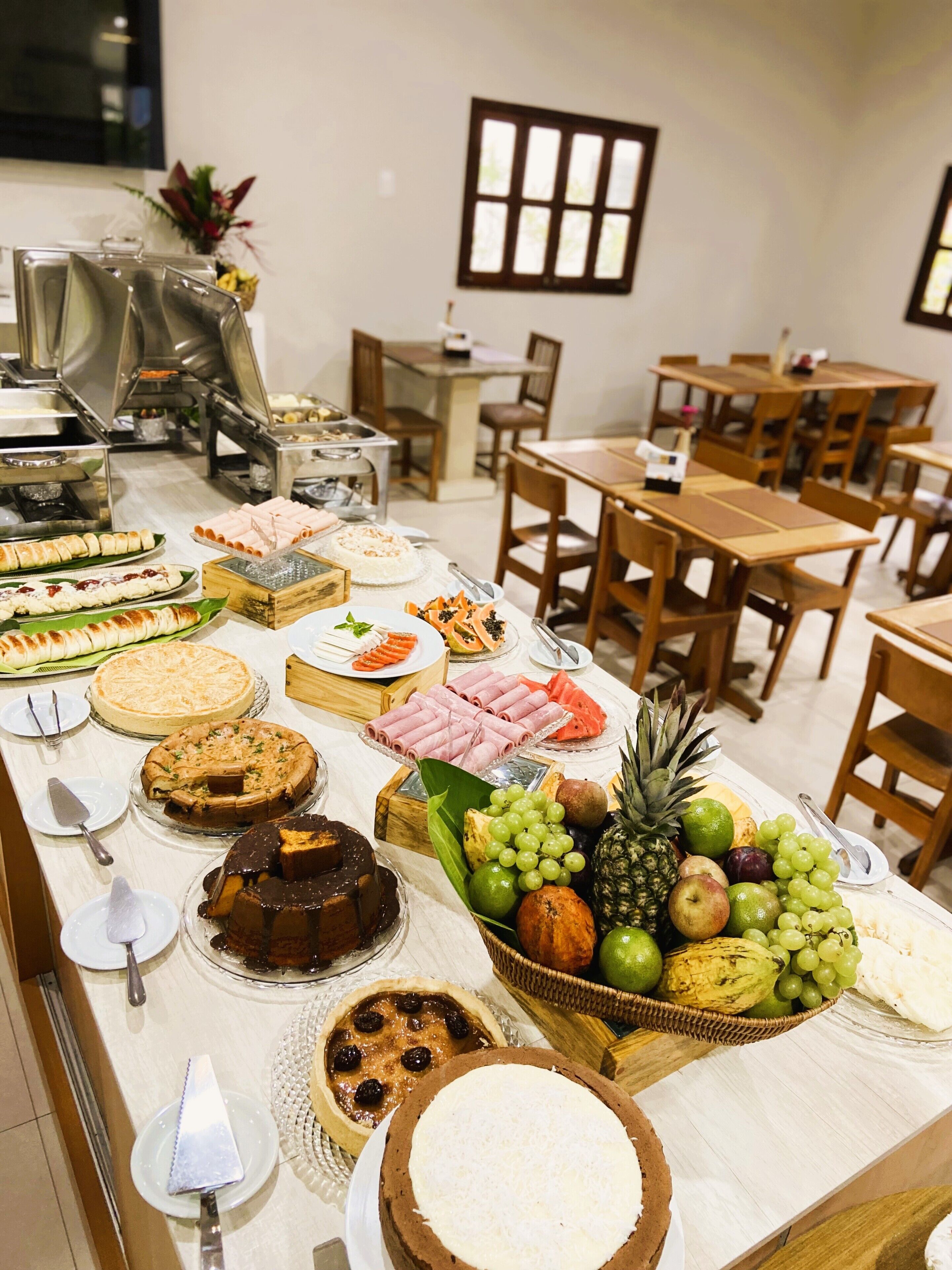 Uma mesa de buffet com diversos tipos de comida e uma saladeira de frutas.
