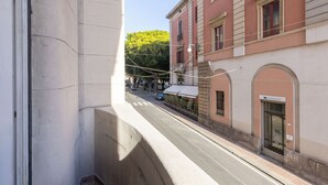 Vista da rua com um edifício de fachada vermelha, entrada gradeada e placa visível.