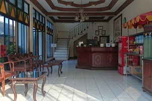 Um saguão de hotel com balcão de recepção, escada e área de estar.