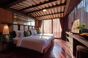 Quarto de hotel com uma cama grande, teto de madeira e área de refeições com mesa e cadeiras.