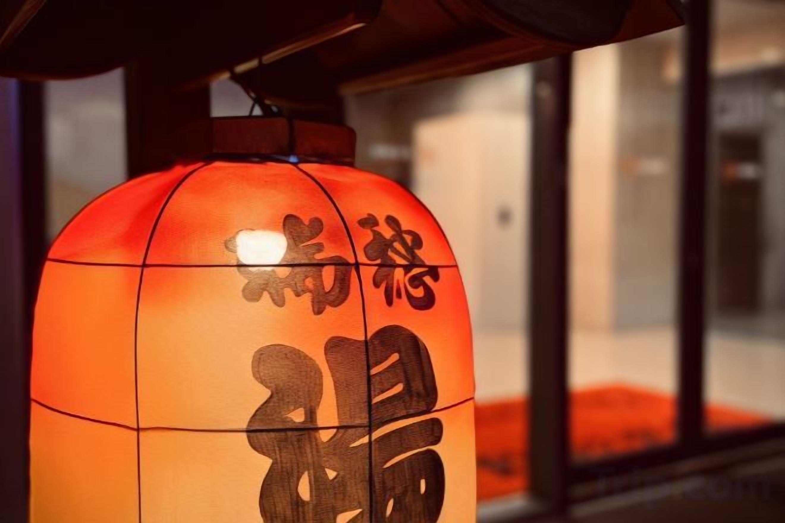 Lanterna japonesa tradicional com caligrafia, pendurada em ambiente interno.