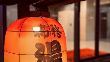 Lanterna japonesa tradicional com caligrafia, pendurada em ambiente interno.