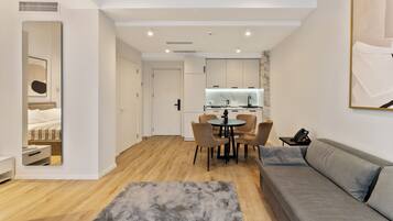 Uma sala de estar moderna com um sofá cinzento, uma mesa de centro e um espaço de jantar com cadeiras e uma pequena mesa.