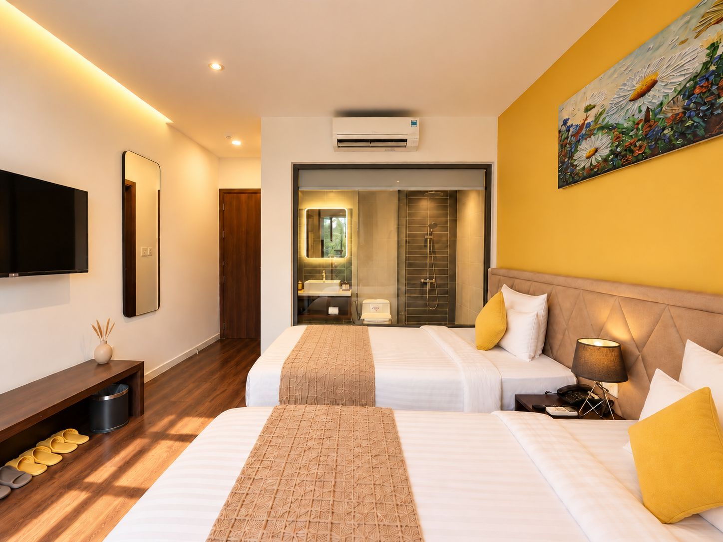 Quarto de hotel com duas camas, televisão, um quadro e banheiro com chuveiro.