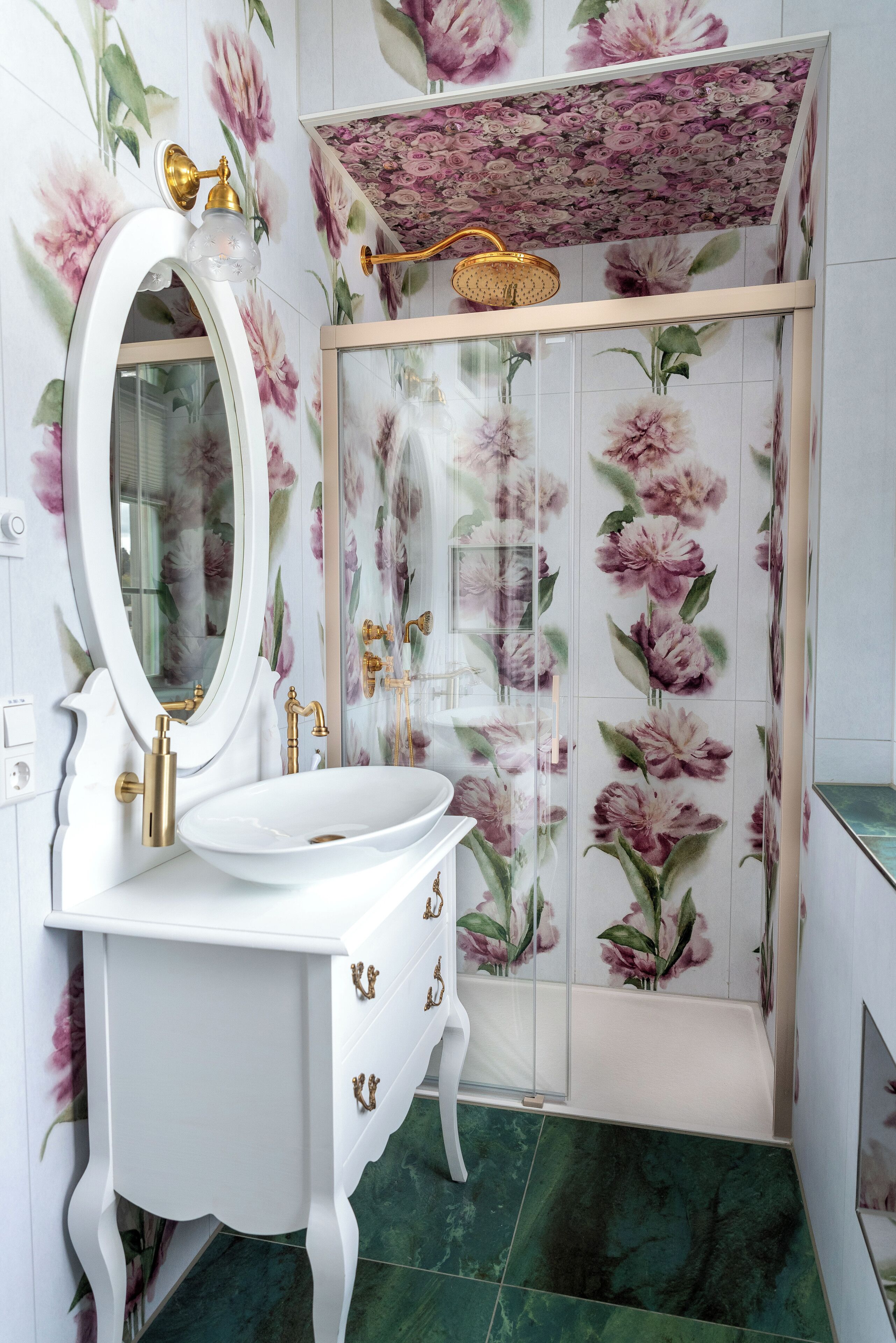 Casa de banho com toucador branco, espelho grande, torneira dourada e papel de parede floral.