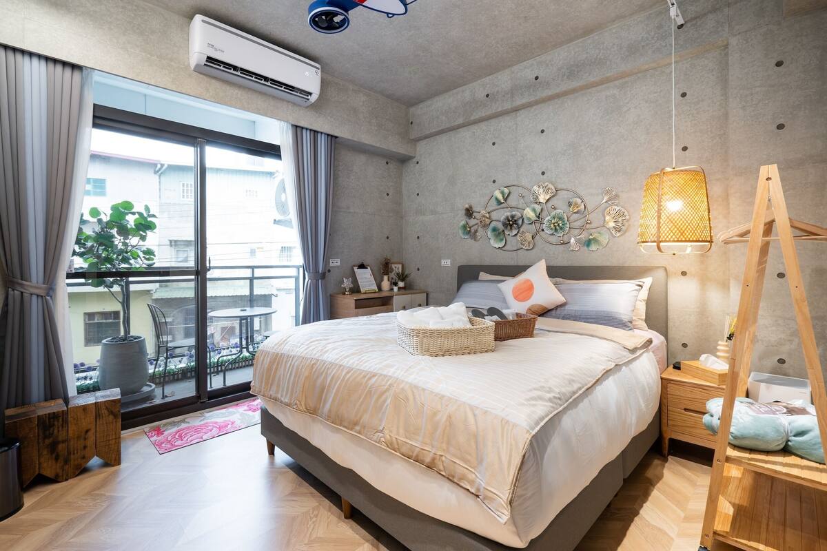 Quarto moderno com uma cama grande, vista para uma varanda e um objeto decorativo na parede.