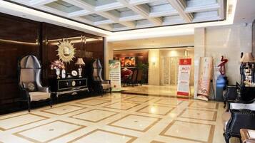 Um hall de hotel com piso de padrão geométrico, um balcão de recepção e um grande candelabro.